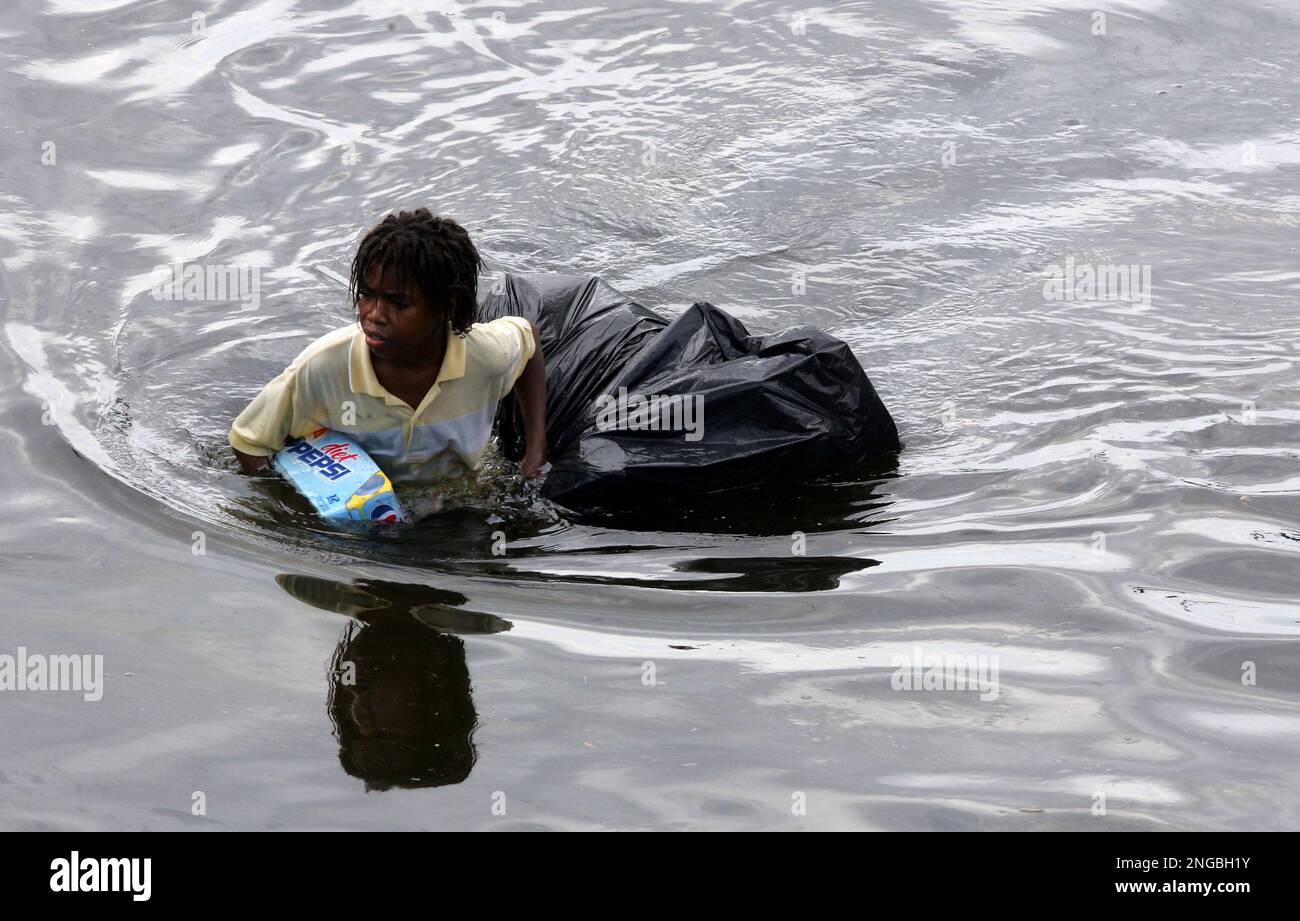 A young man walks through chest deep flood water after looting a ...
