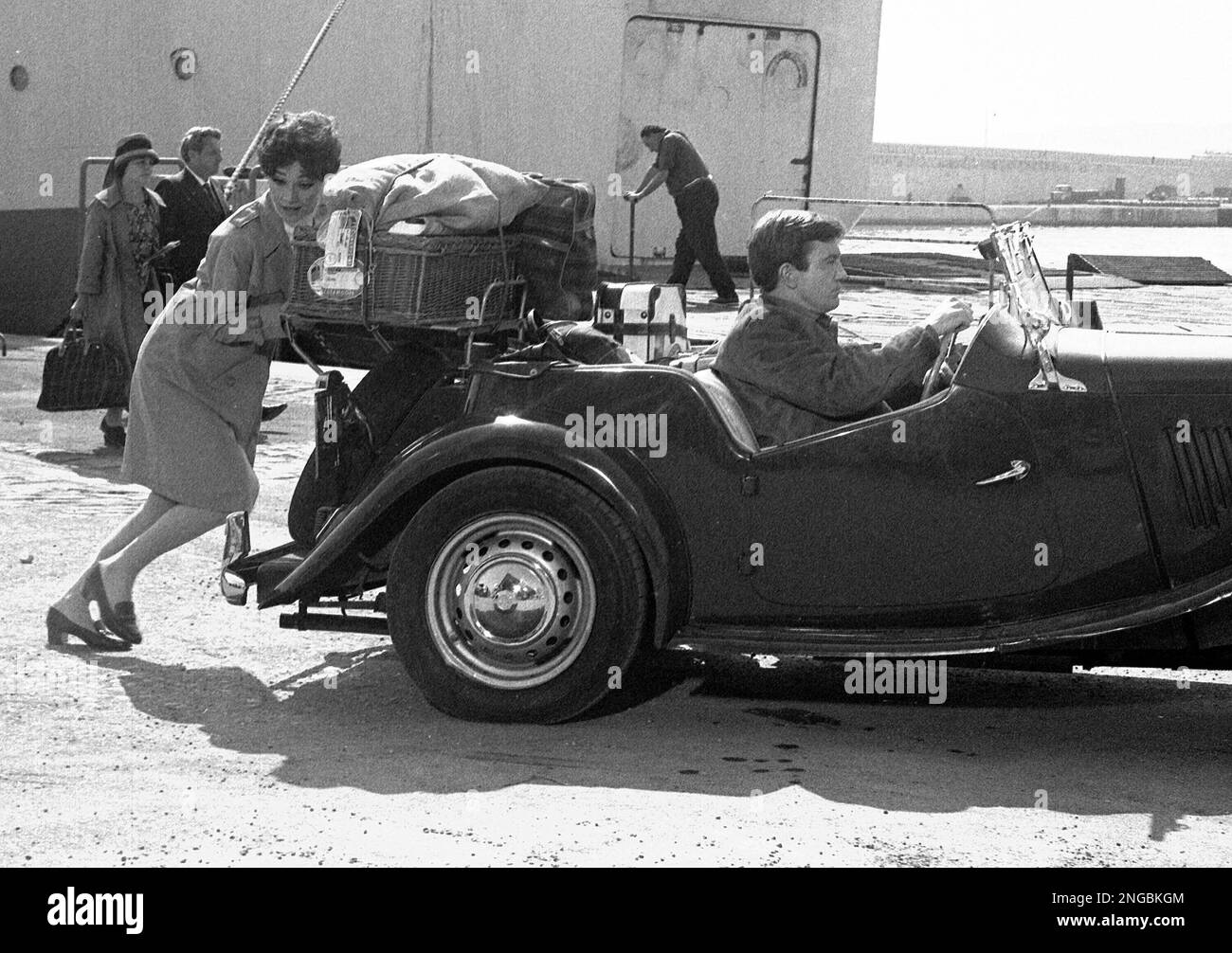 British actor Albert Finney steers his sportscar as actress Audrey ...