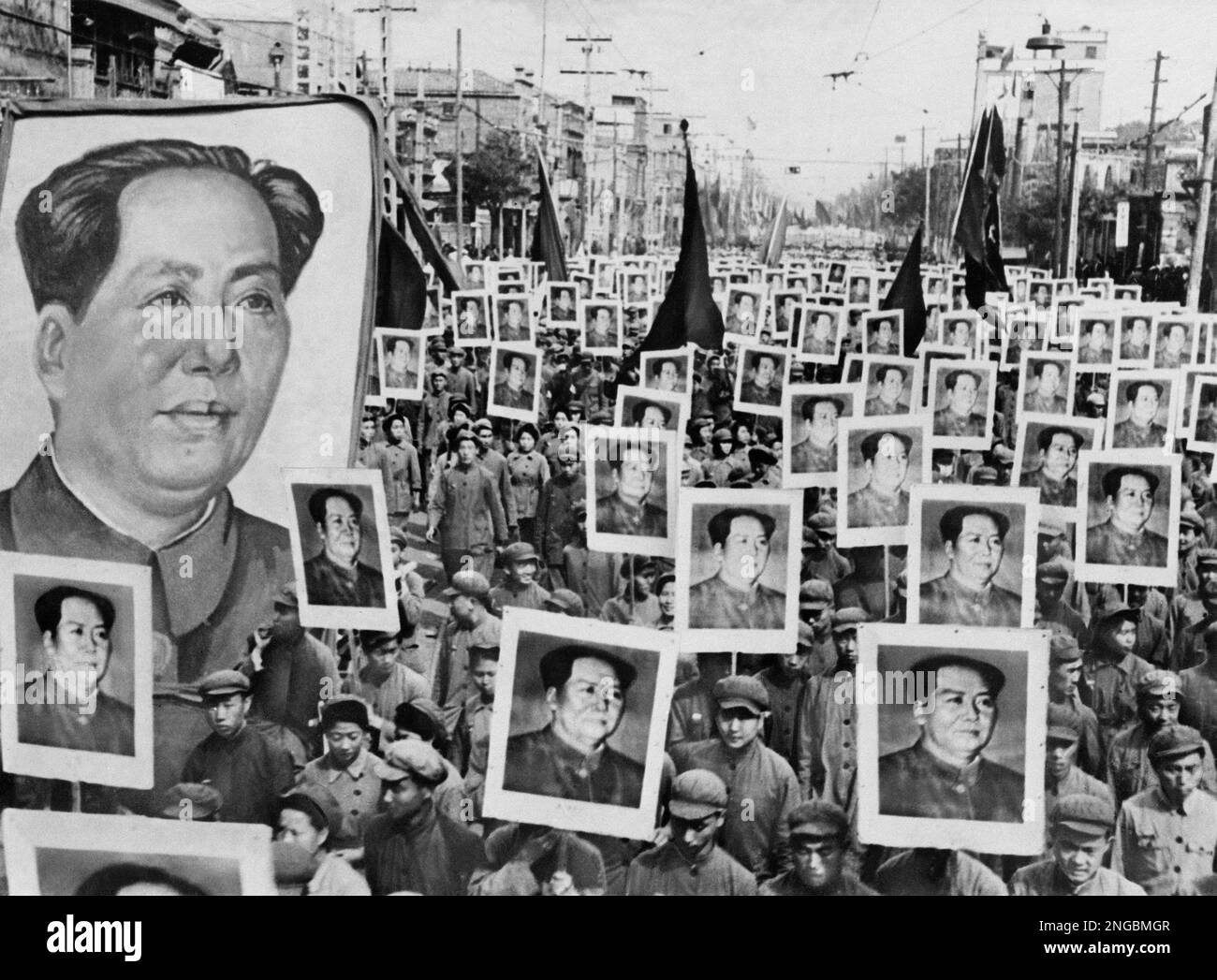 Crowds holding posters of Mao Zedong fill the street of a city in China ...