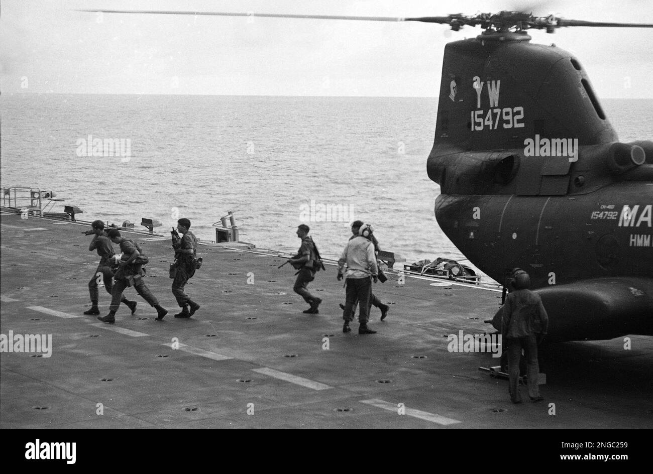 U.S. Marines debark from a Chinook helicopter aboard the deck of the ...