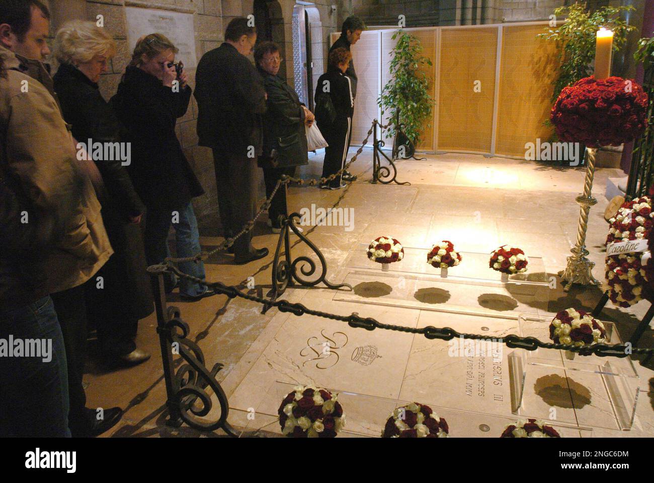 Tourists pass Prince Rainier's grave, foreground, and his late wife ...