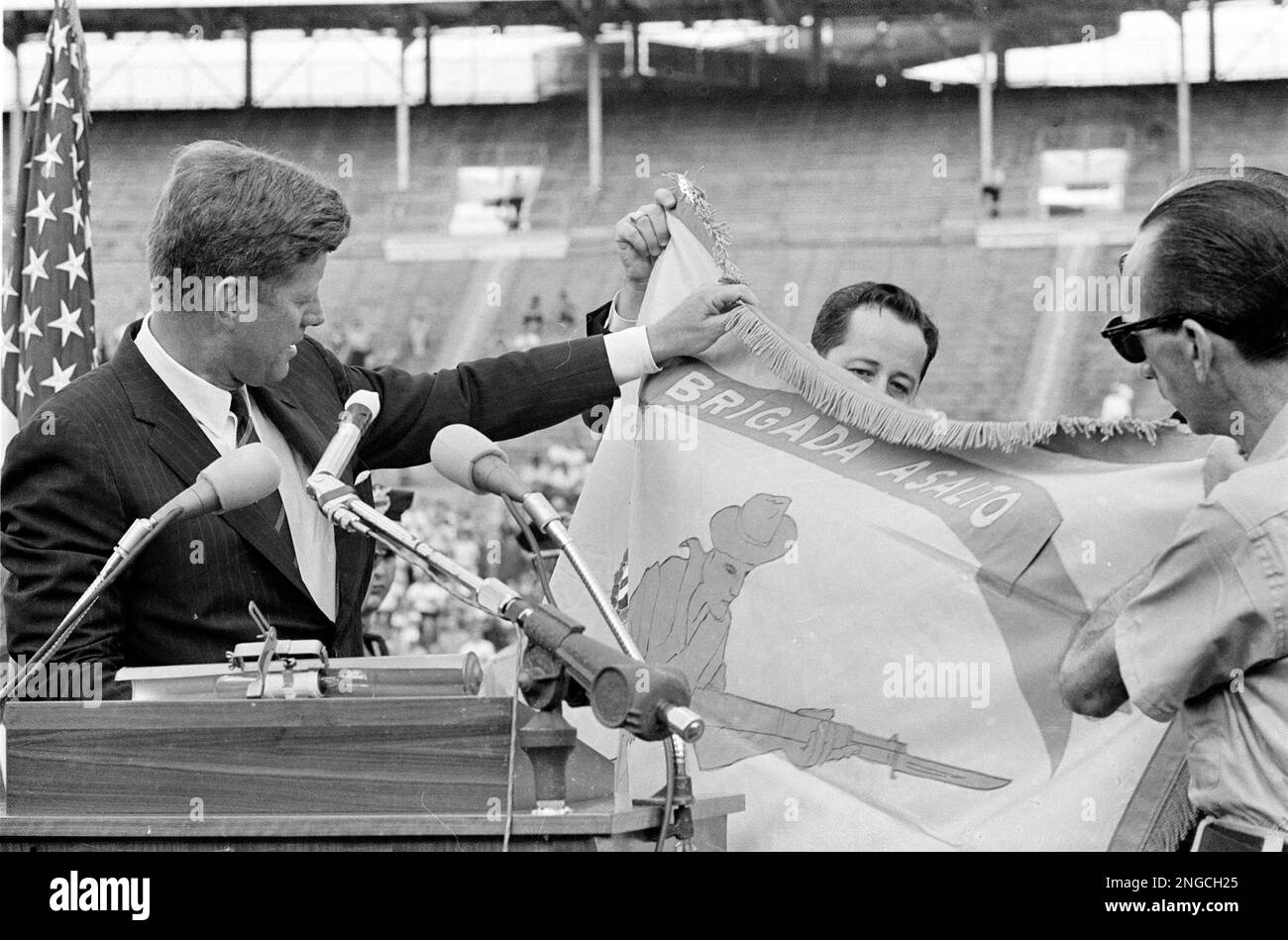 U.S. President John F. Kennedy, left, receives the combat flag of the ...