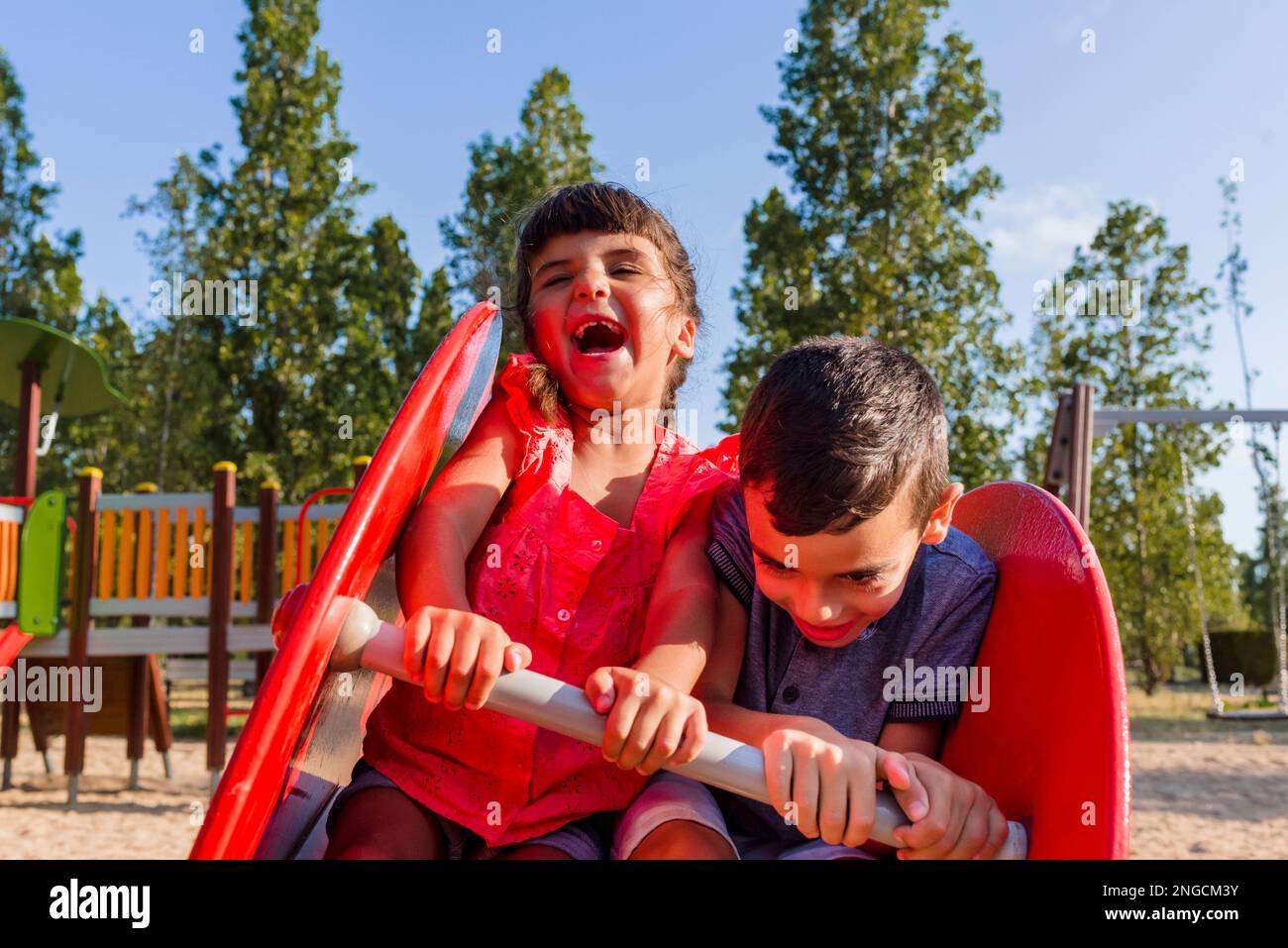 Two kids having fun playing together on a playground in a park Stock ...