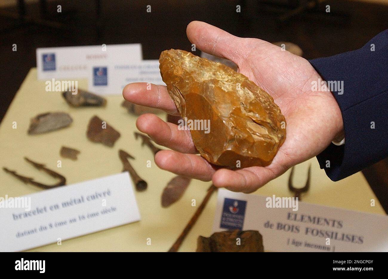 A customs officer holds a the two-sided cut stone tool seen dating from ...