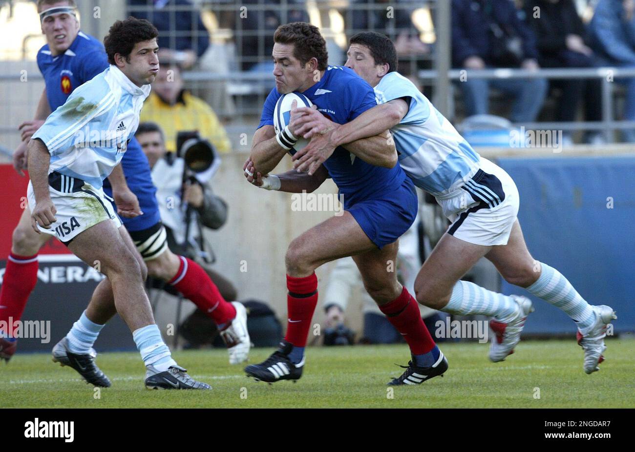 French rugby player Tony Marsh, center, hangs on to the ball as he is ...