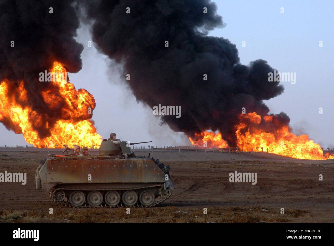 An armored U.S. military vehicle passes near a burning oil pipeline on ...
