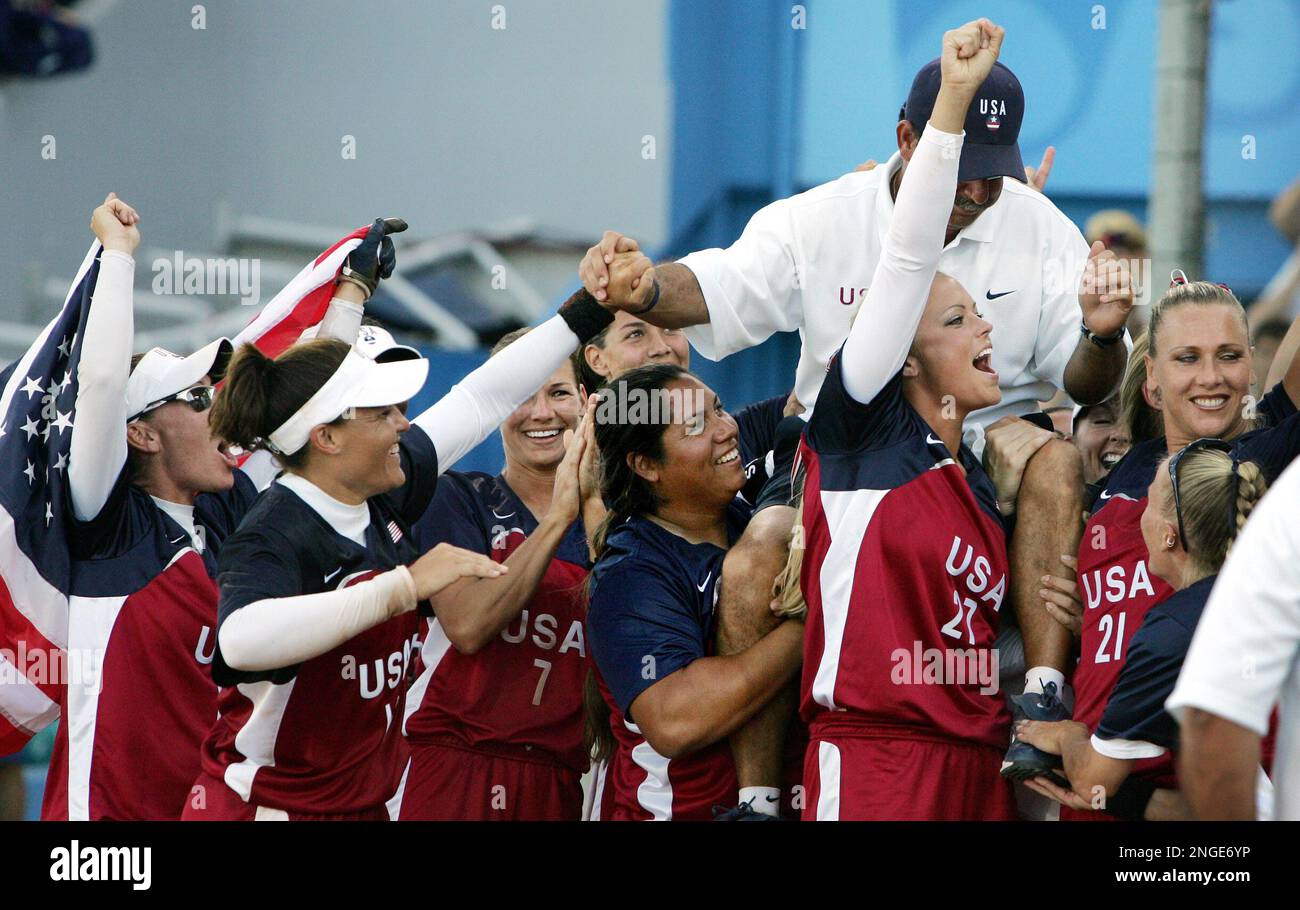 Members fo the United States softball team lift their coach Mike ...