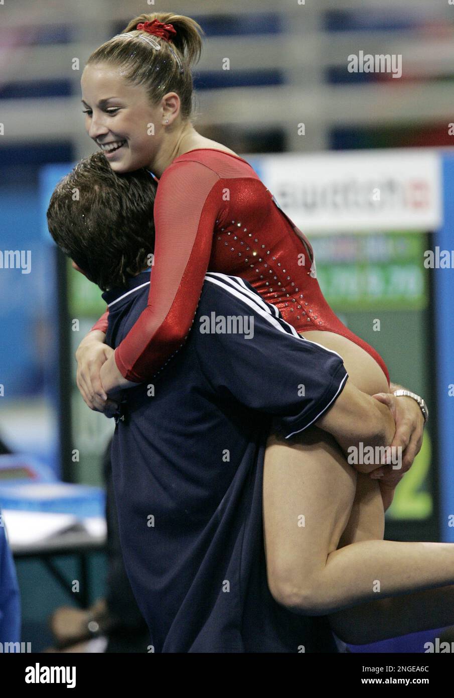 Carly Patterson, of the United States, is hoisted by her coach Evgeny ...