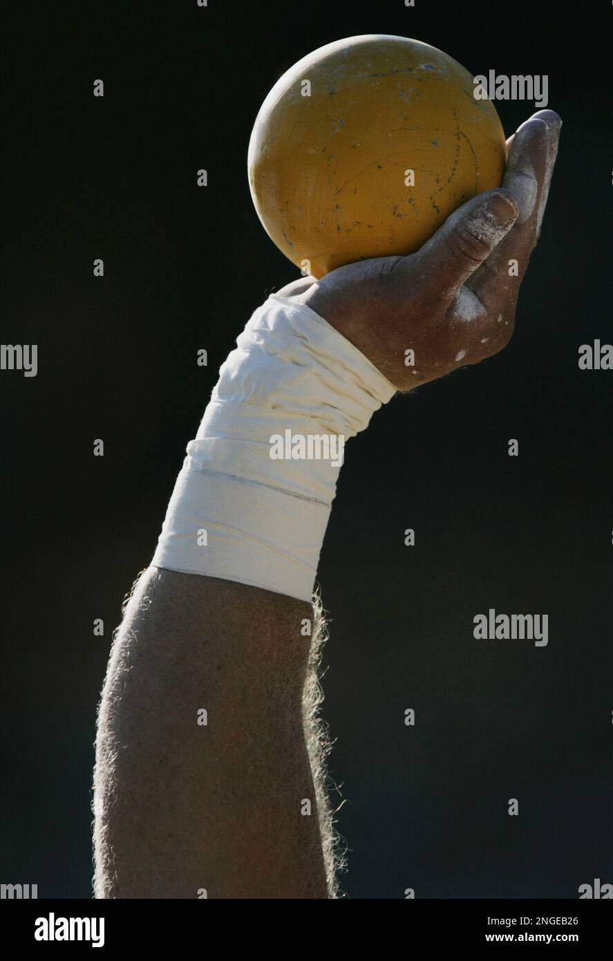 John Godina holds up the shot put before attempting his third throw ...