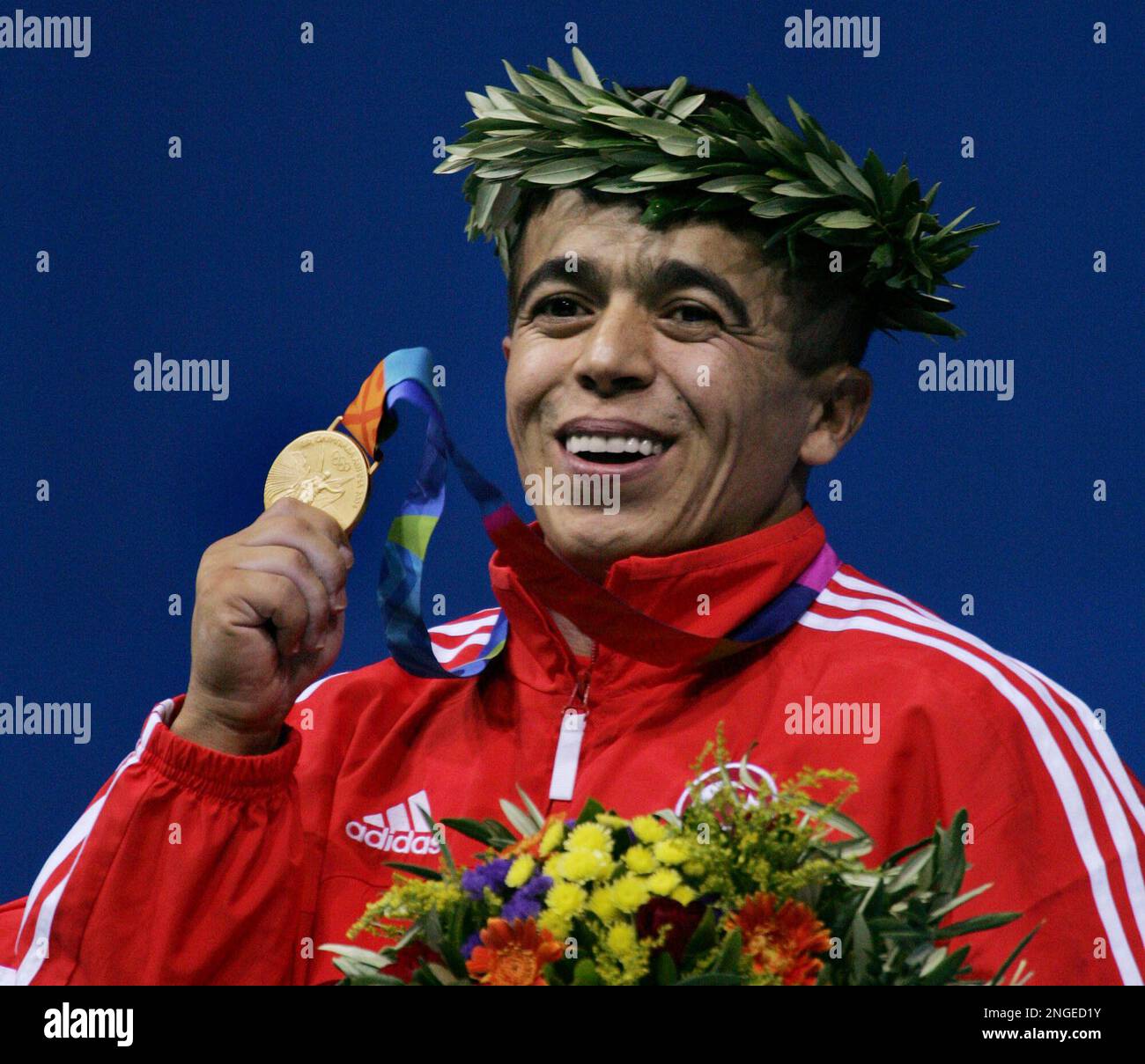 Turkish 56 kg weightlifter Halil Mutlu smiles as he holds up his gold ...