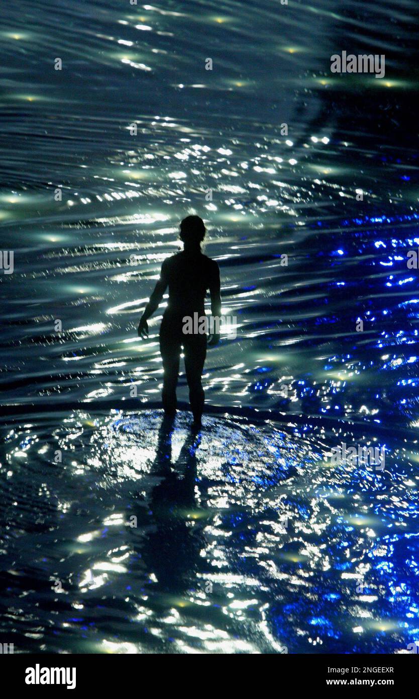 A performer stands in a pool of water during the Opening Ceremony of ...