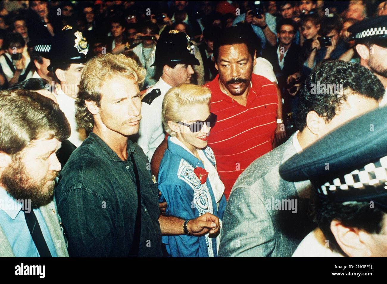 U.S. pop star Madonna is escorted through crowds of screaming fans at ...