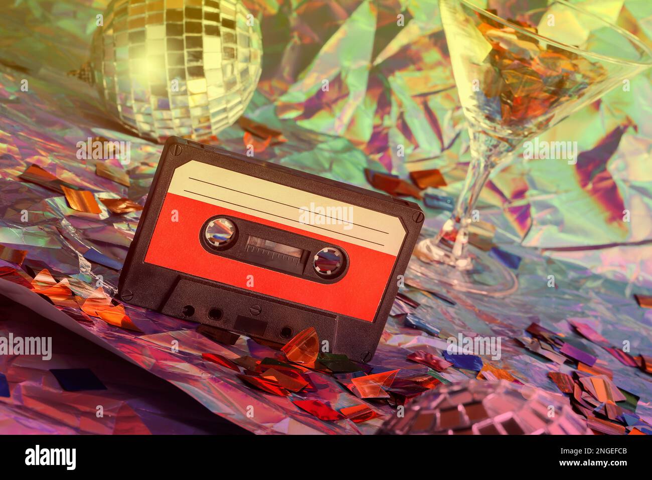 old cassette tape, disco ball and cocktail glass on crumpled neon ...