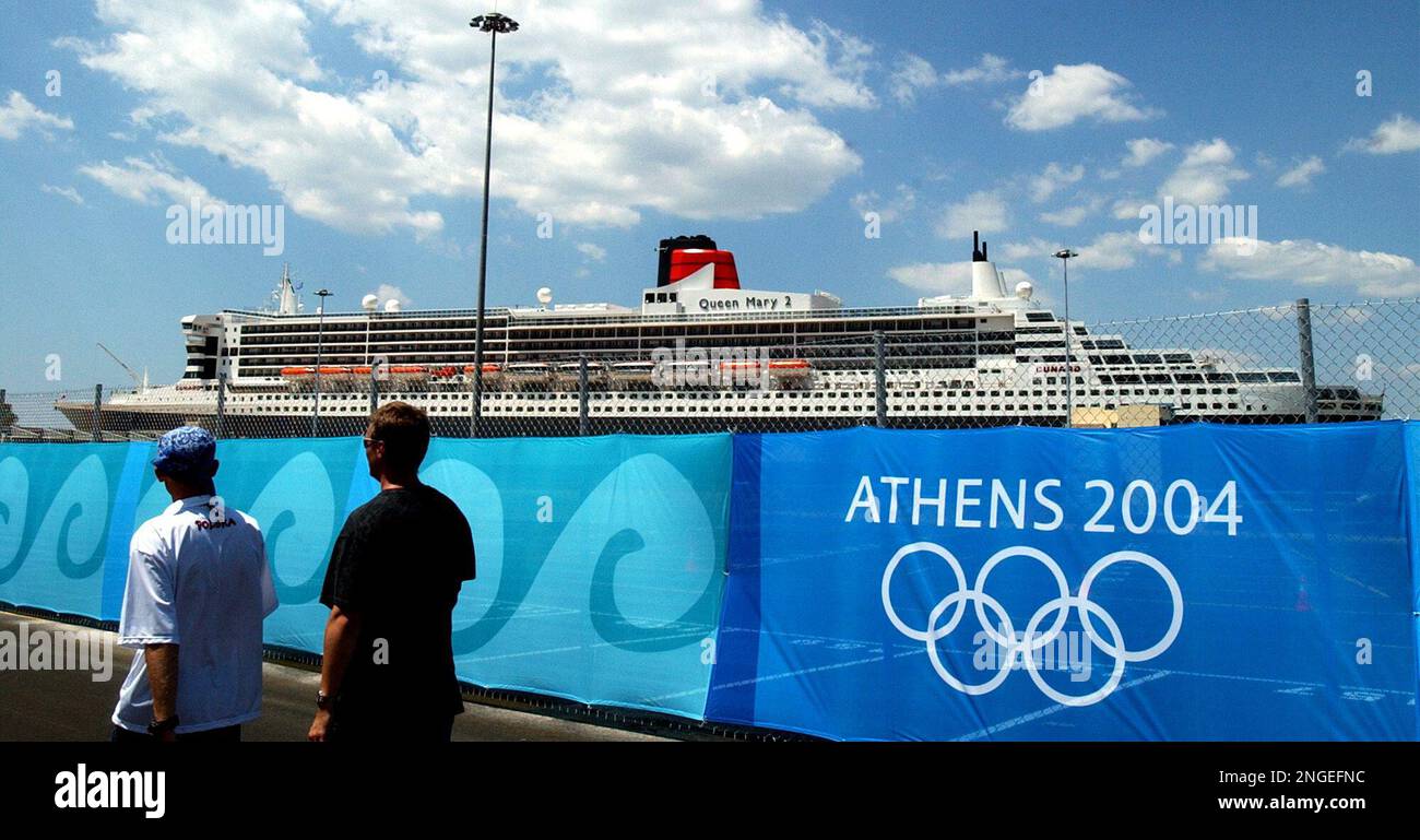 Passengers walk past the Queen Mary 2 cruise ship, in the main port of ...