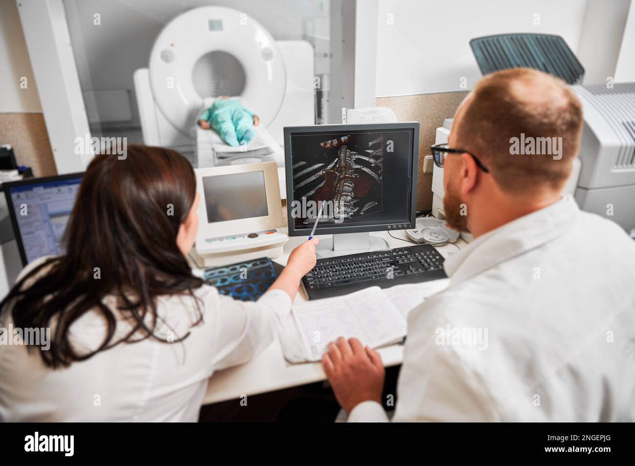 Medical computed tomography or MRI scanner. Back view of two doctors ...