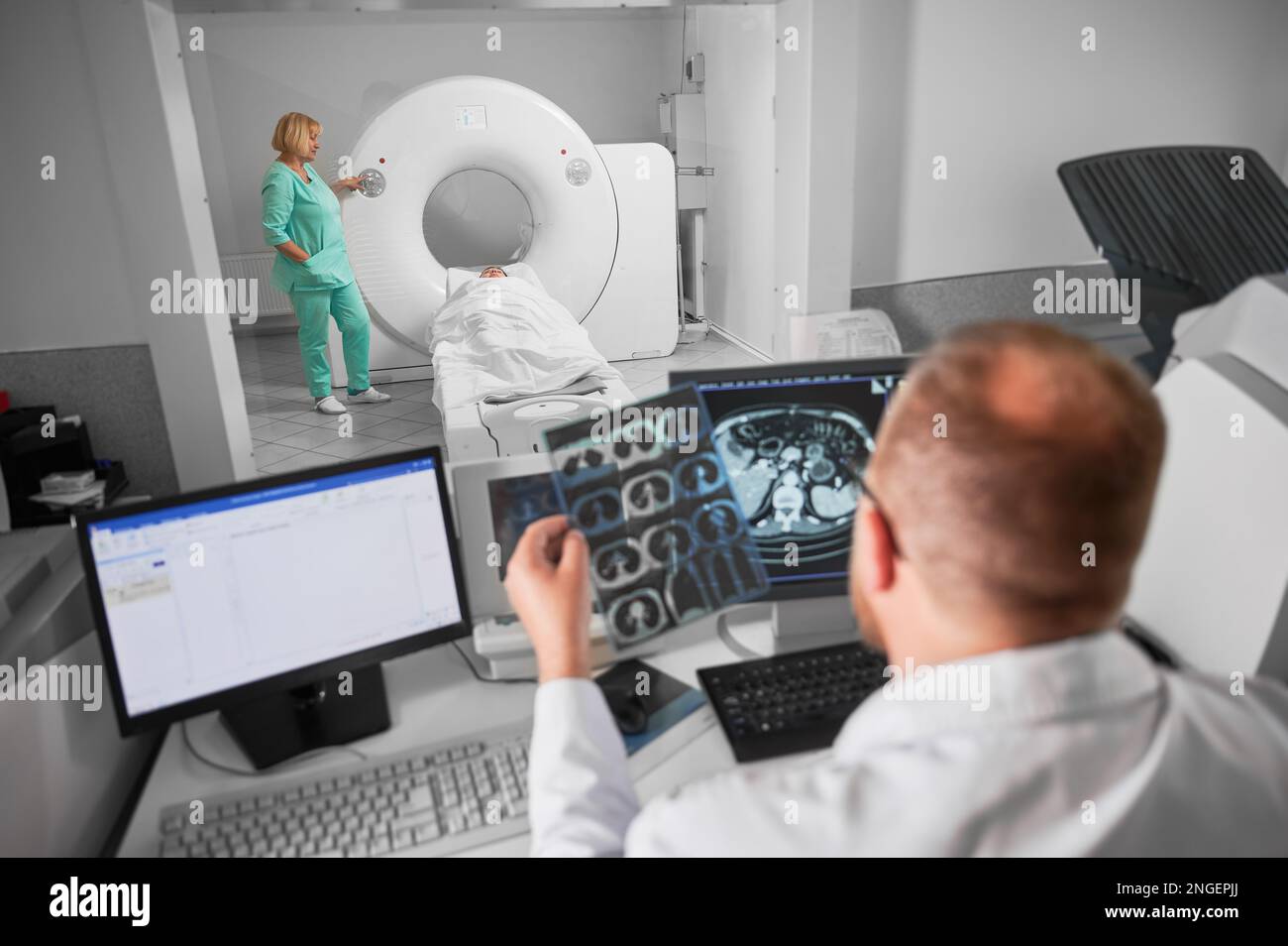 Medical computed tomography or MRI scanner. Back view of male doctor ...