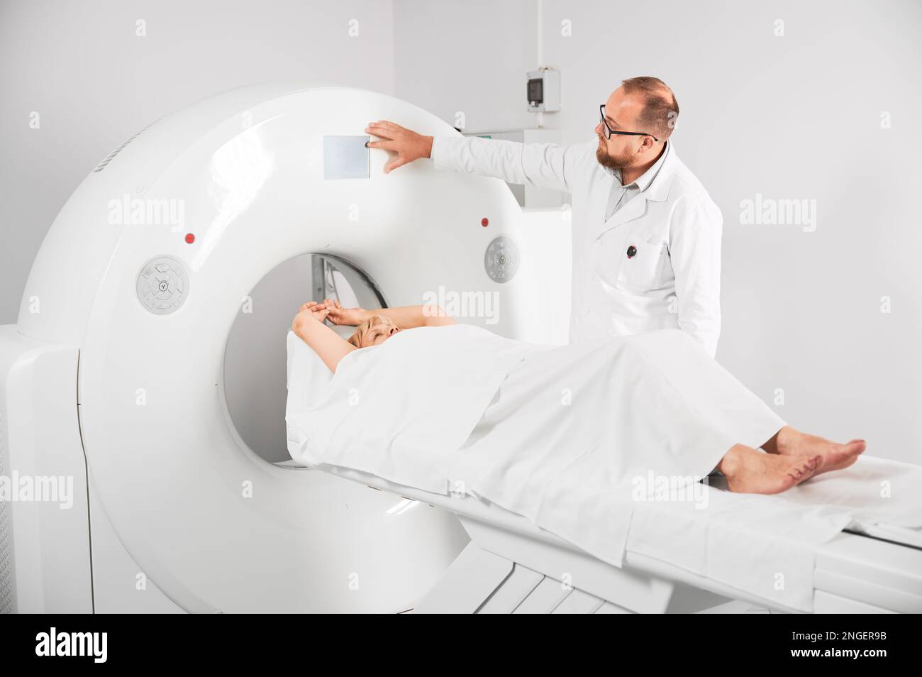 Medical computed tomography or MRI scanner. Male radiologist presses ...