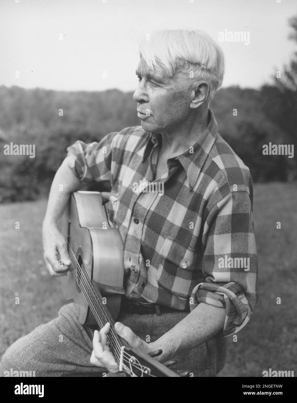 American poet Carl Sandburg is shown playing guitar outside his farm in ...