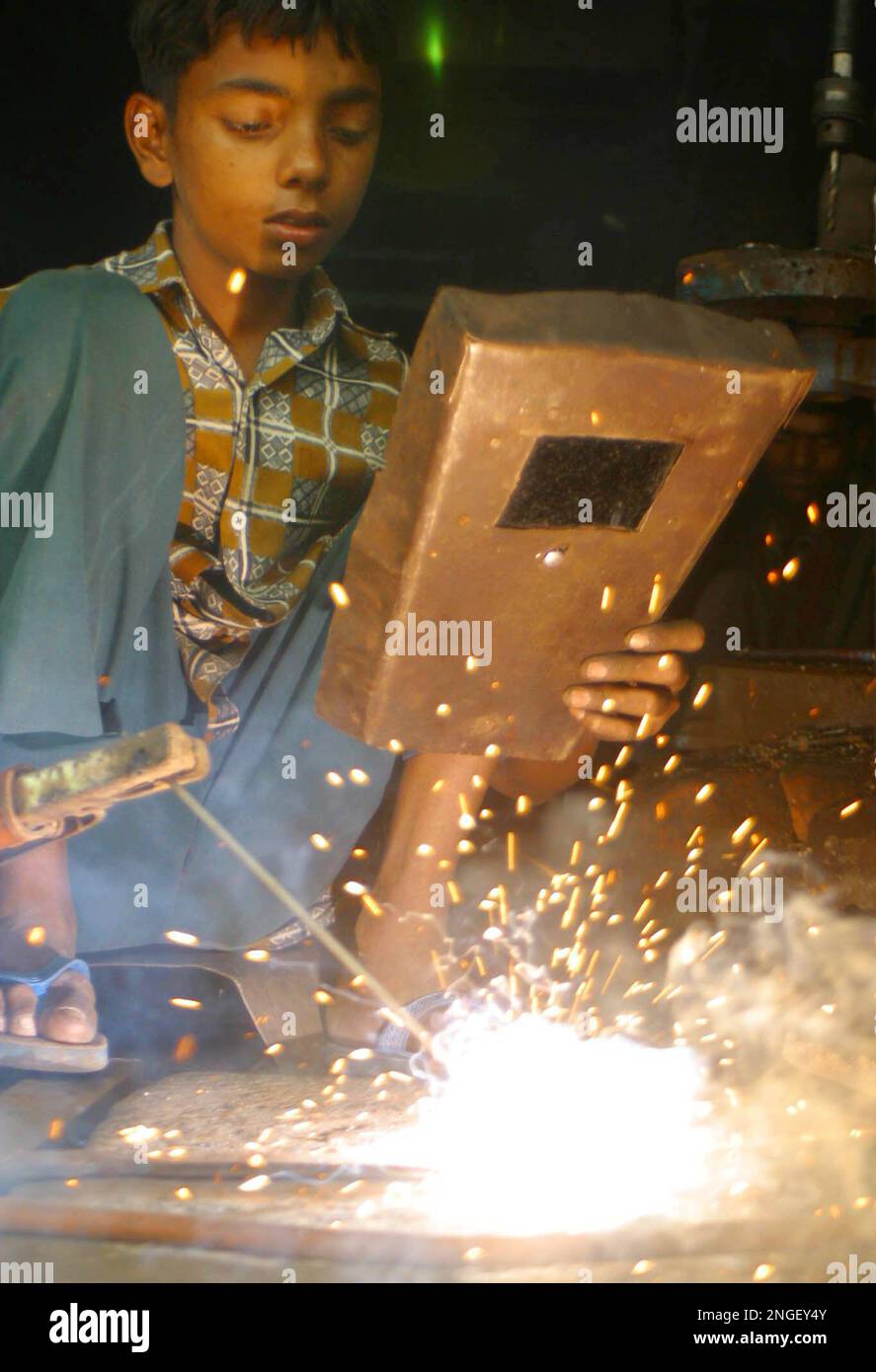 A young boy works on a welding machine at a fabrication unit in ...