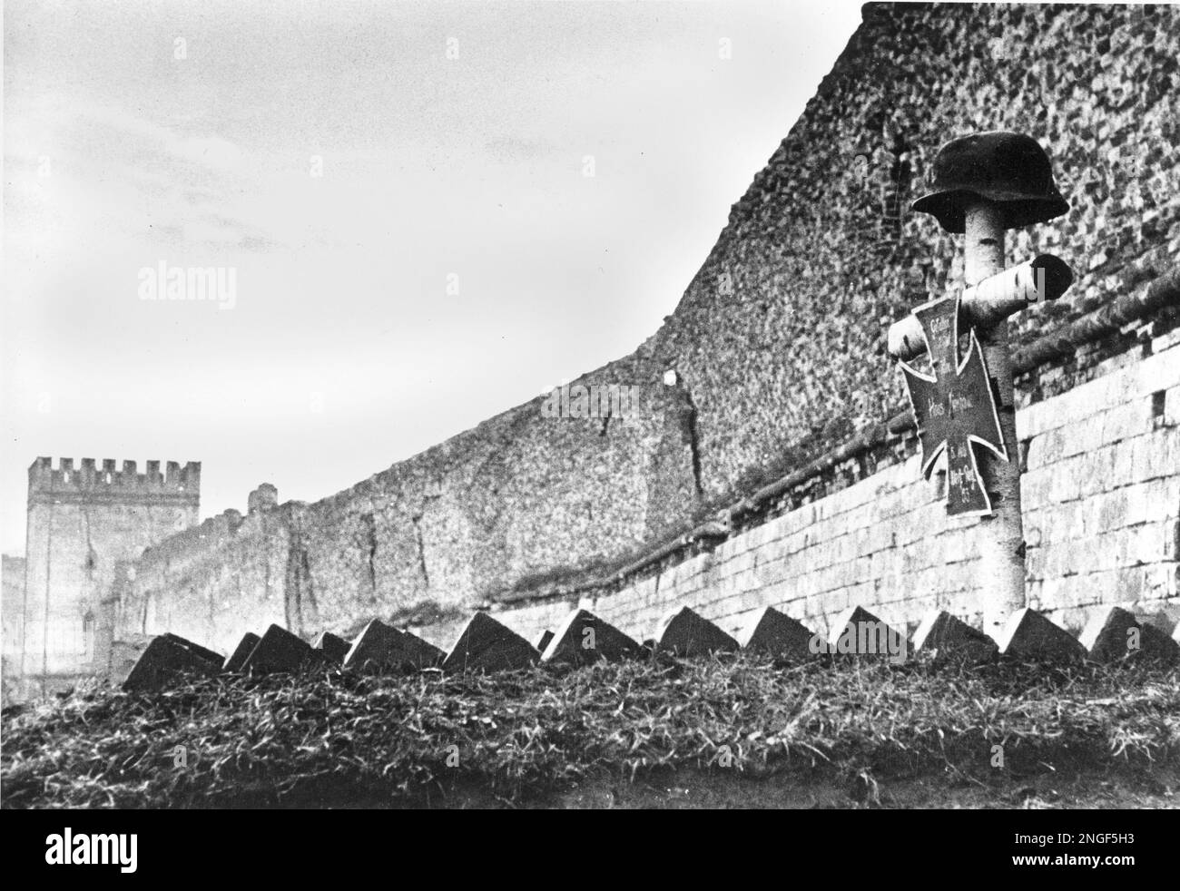 A wooden cross with an iron cross is topped with the helmet of a fallen ...
