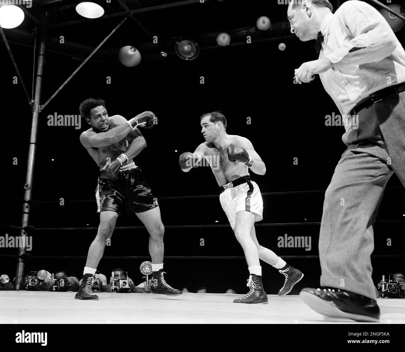 Light heavyweight champion Archie Moore, in black trunks, backs away as ...