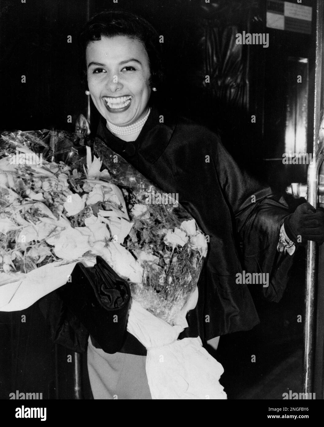 American actress-singer Lena Horne carries a bouquet of flowers as she ...