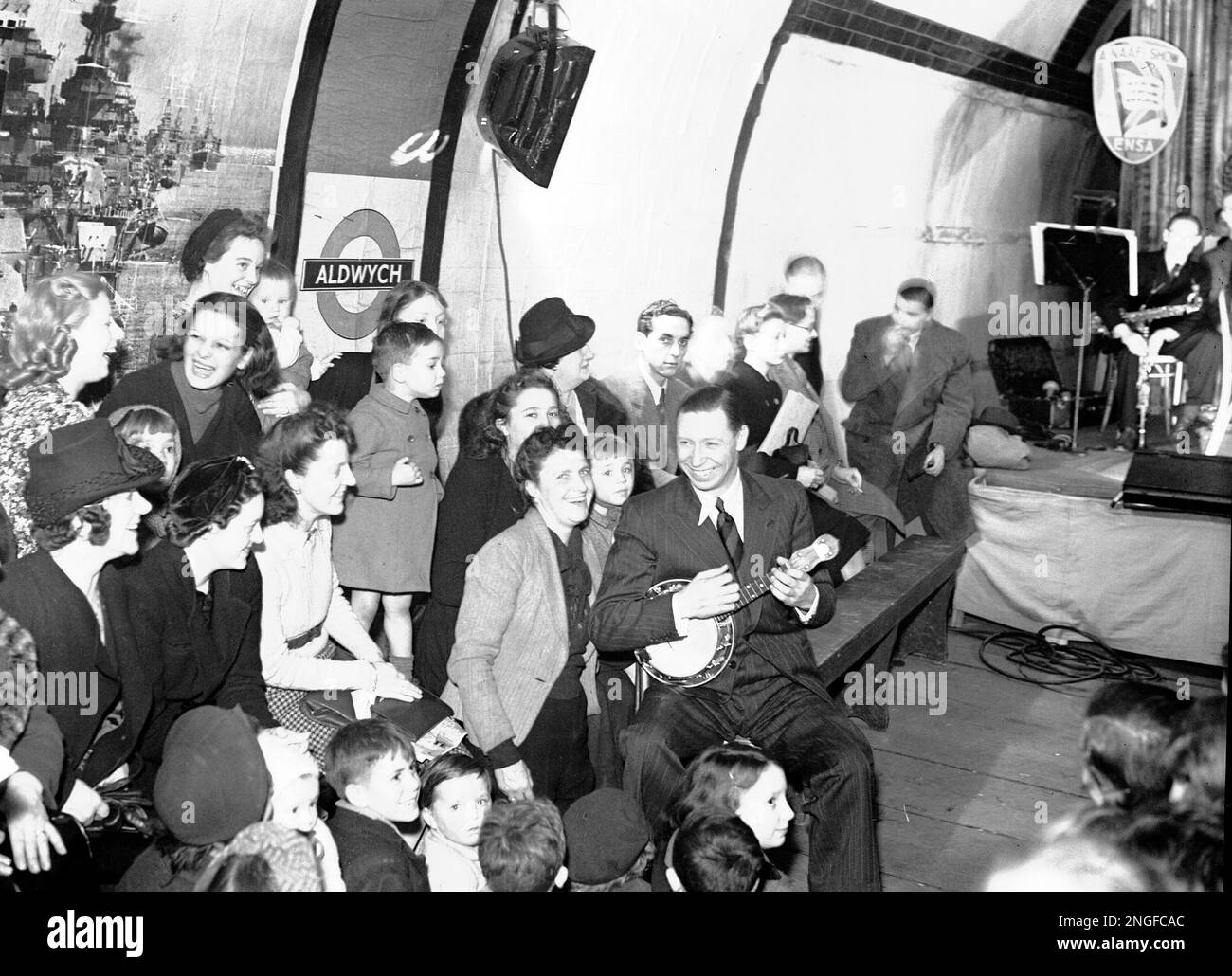 British comedian and actor George Formby, centre playing his ukulele ...