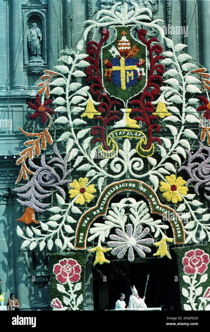 Pope John Paul II, wearing miter, is shown underneath a large flower ...