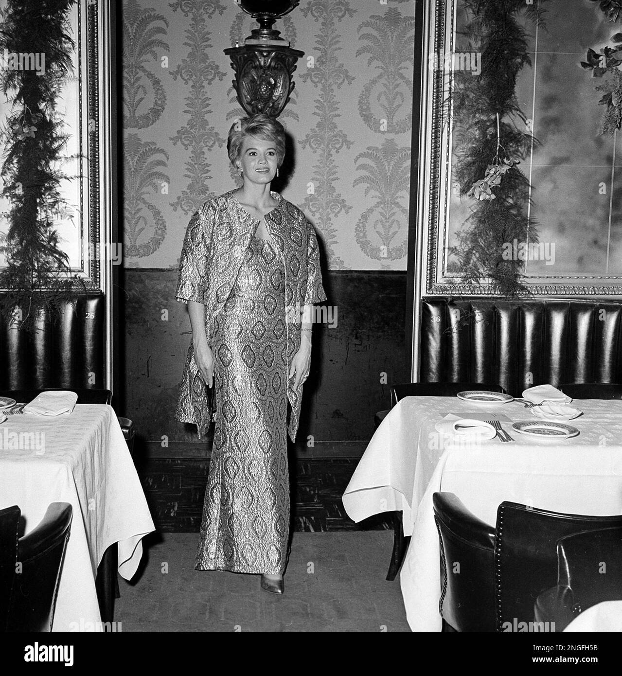American actress Angie Dickinson is wearing a gold brocade fitted gown ...