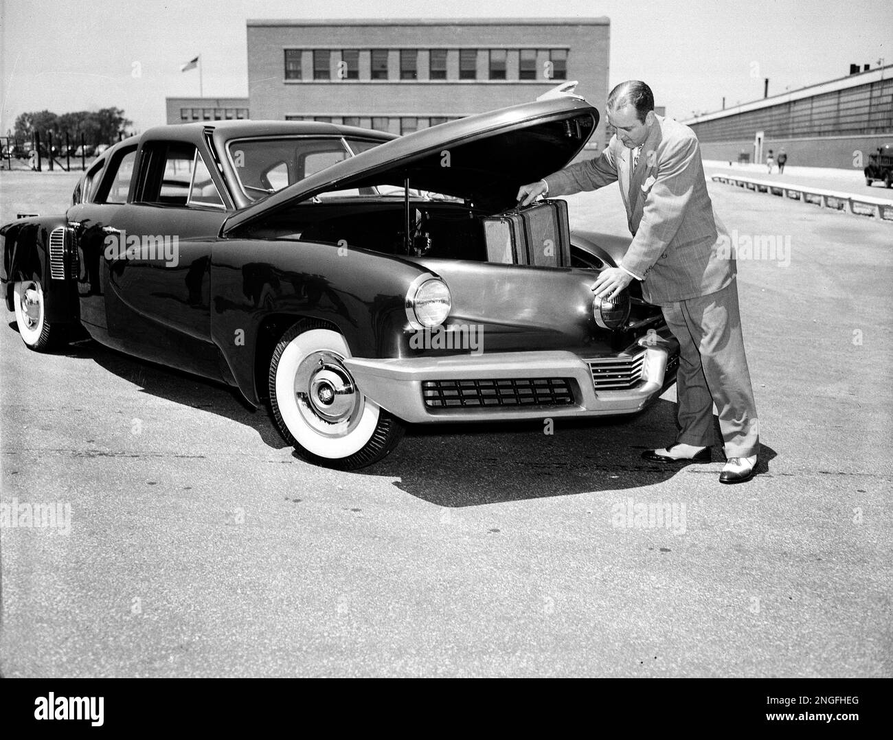 Preston Tucker, 44-year-old car designer, places a piece of luggage in ...