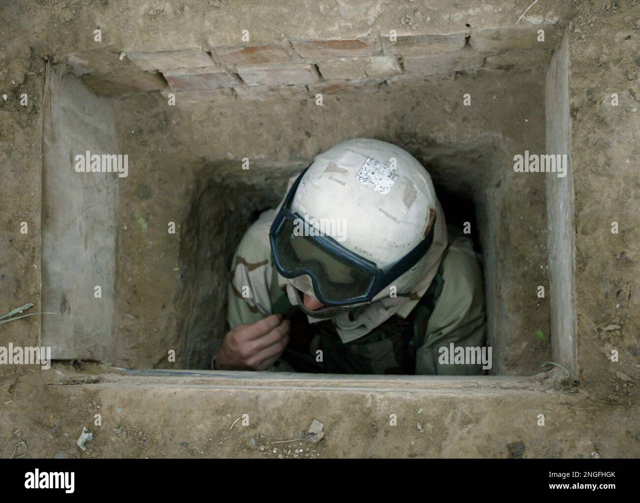 A U.S. soldier demonstrates access to the spider hole used by Saddam ...