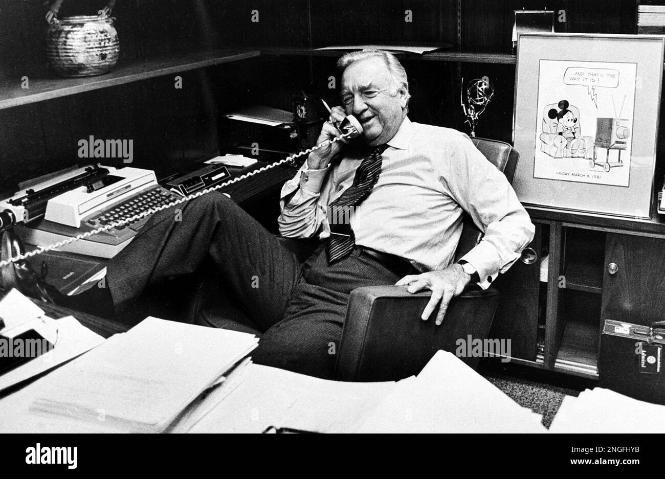 TV news anchorman Walter Cronkite talks on the phone at his office ...