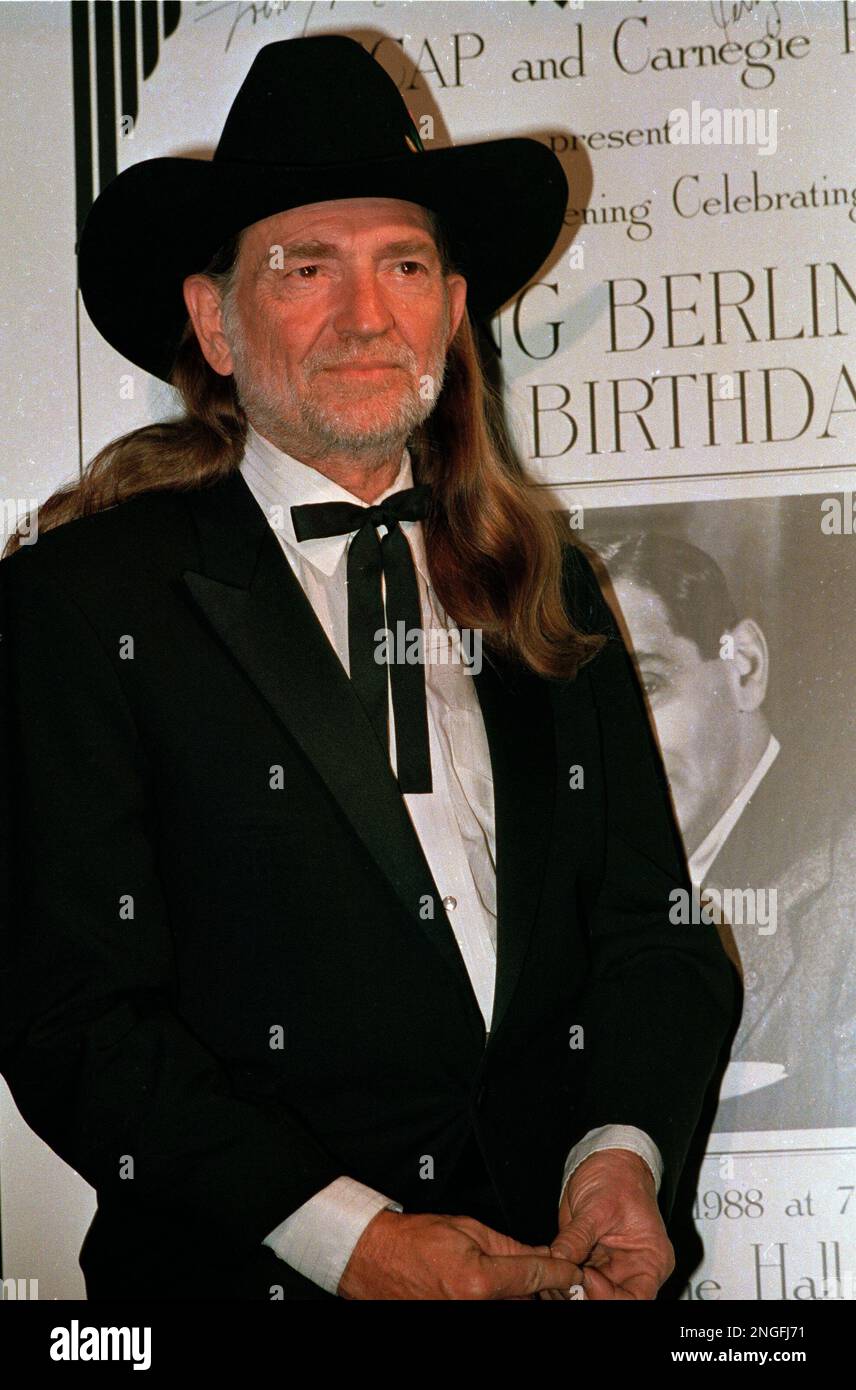 Singer Willie Nelson poses in front of a poster announcing a concert to ...