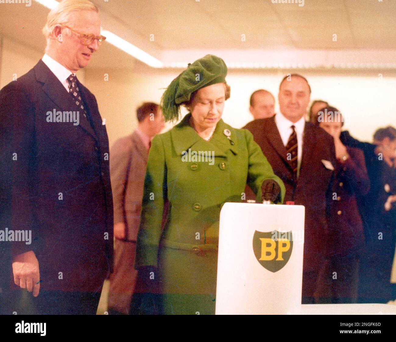 Britain's Queen Elizabeth II, presses a button to start the flow of oil ...