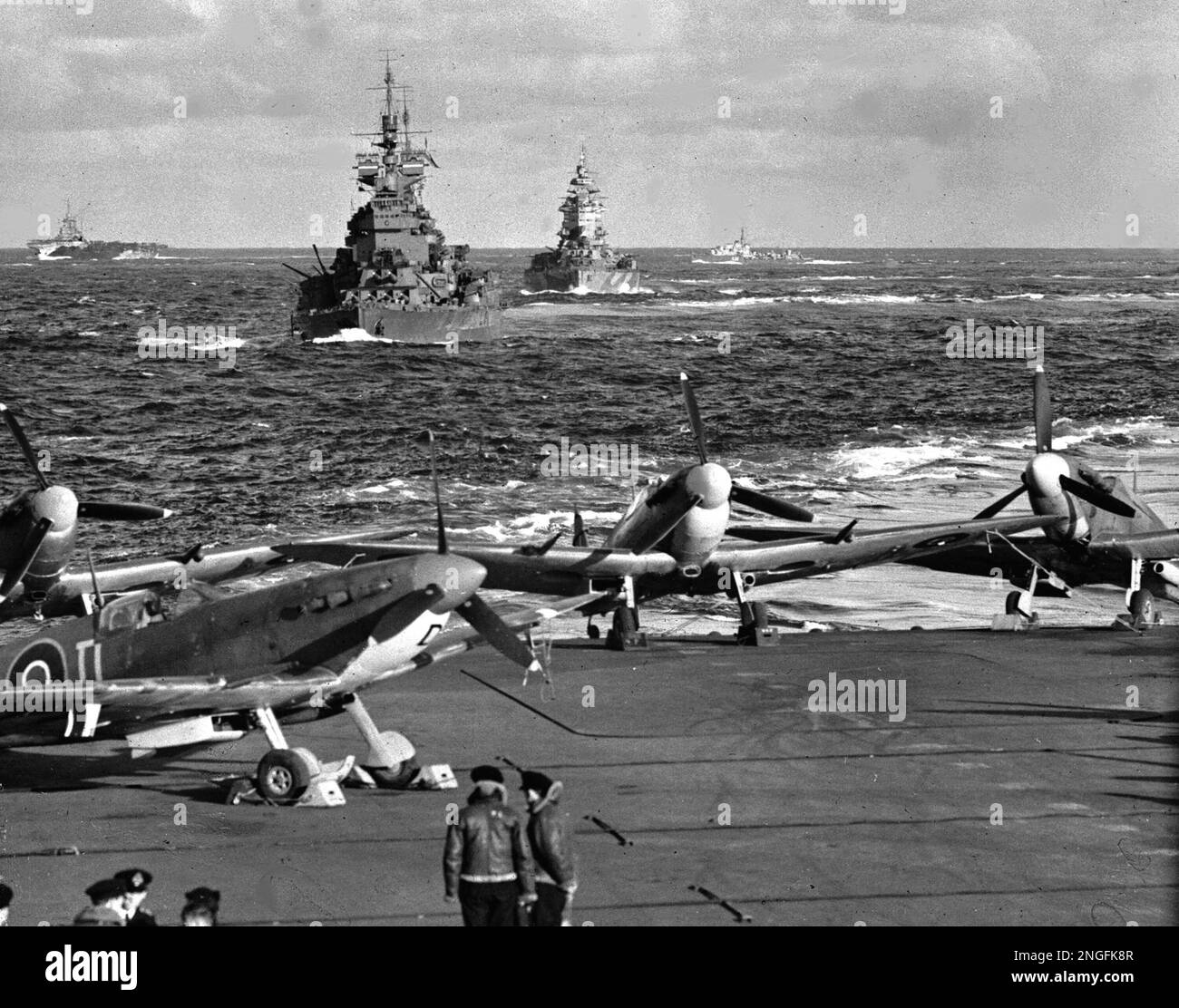 Seafires are seen on the deck of a carrier, foreground, whilst two ...