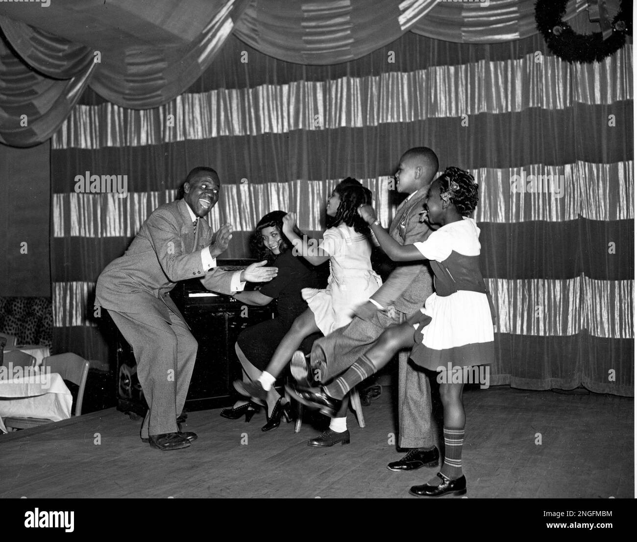 Tap dancer Bill Robinson, known as Bojangles, far left, is assisted by ...