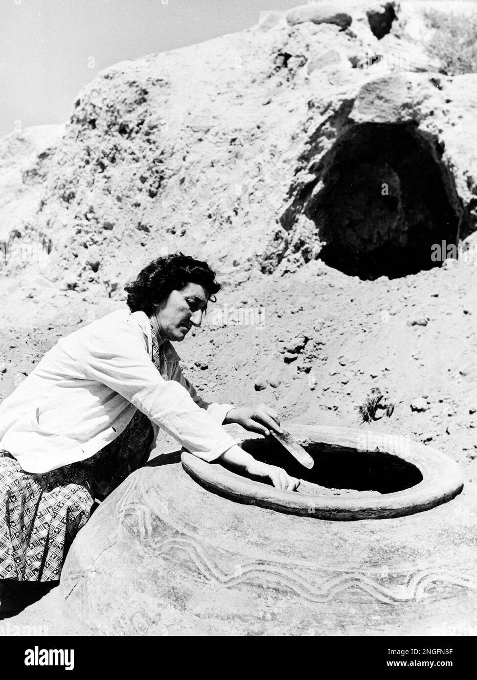 Expedition member M. Vaganian cleans a partially unearthed storage pot ...