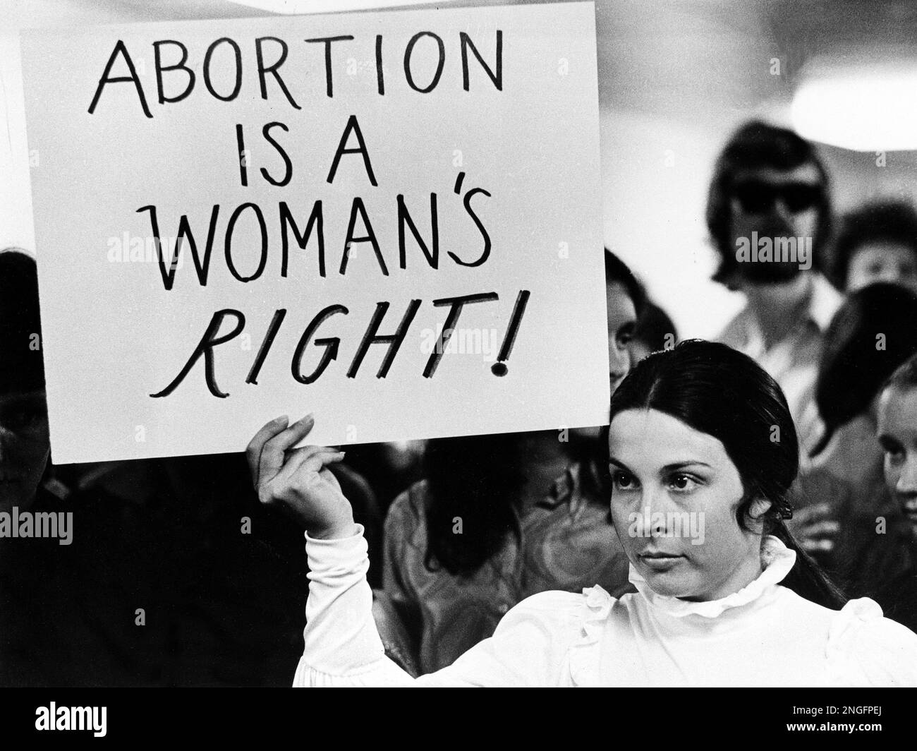 A young woman holds a sign demanding a woman's right to abortion at a ...