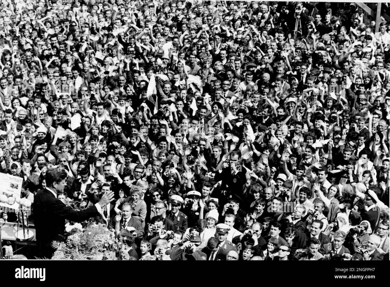 U.S. President John F. Kennedy, left, waves back to a crowd of more ...