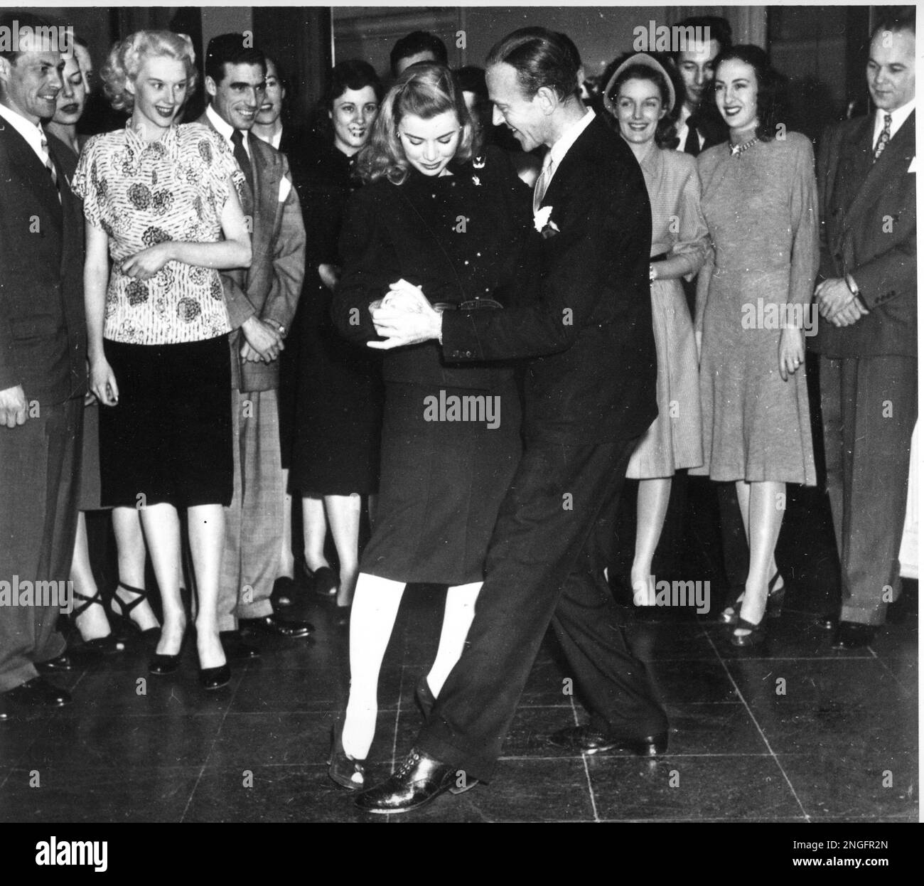 Dancer and actor Fred Astaire demonstrates a dance step with Jo Ann ...