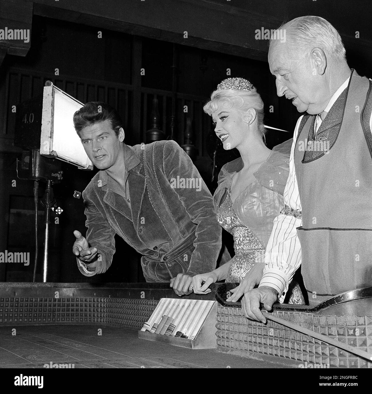 British actor Roger Moore throws the dice while actress Dorothy Provine ...