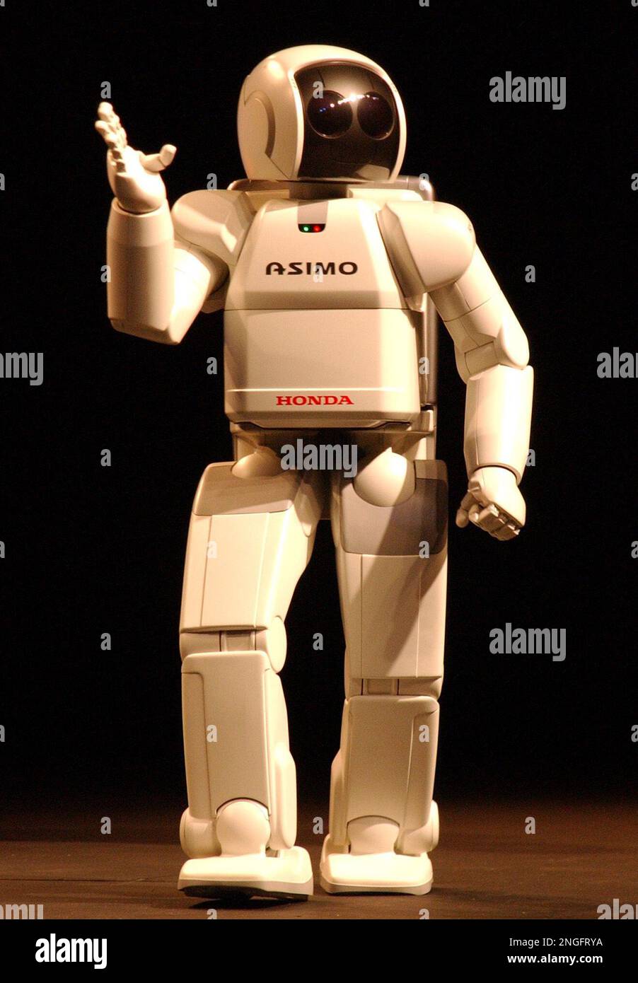 A humanoid robot called ASIMO, developed by Honda Motor Co., waves to ...
