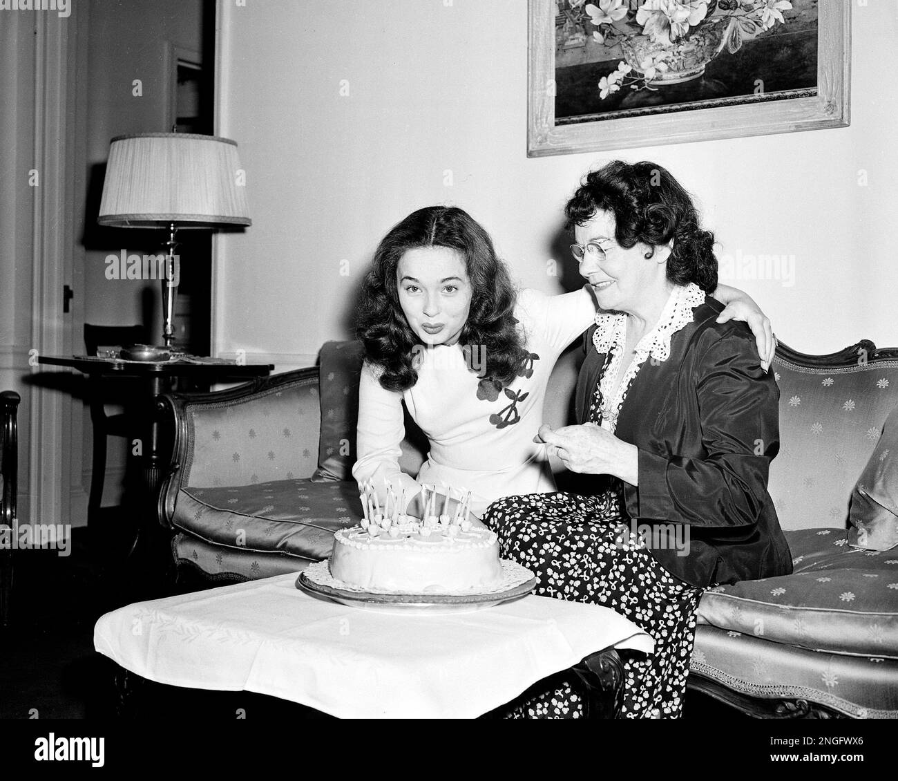 Sitting next to her mother, young actress Ann Blyth is making a wish as ...