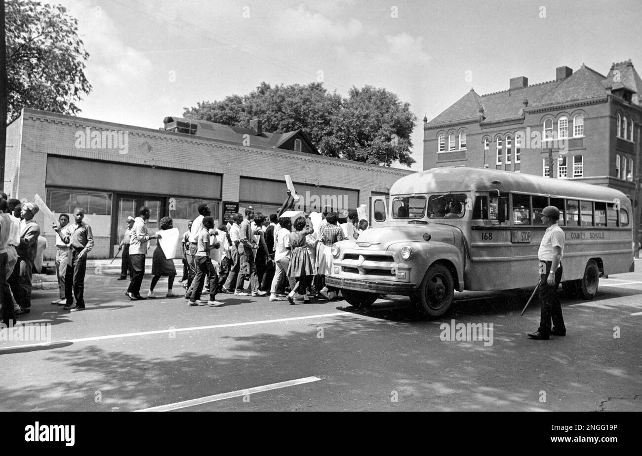 Policemen are leading a group of young black students into a school bus ...