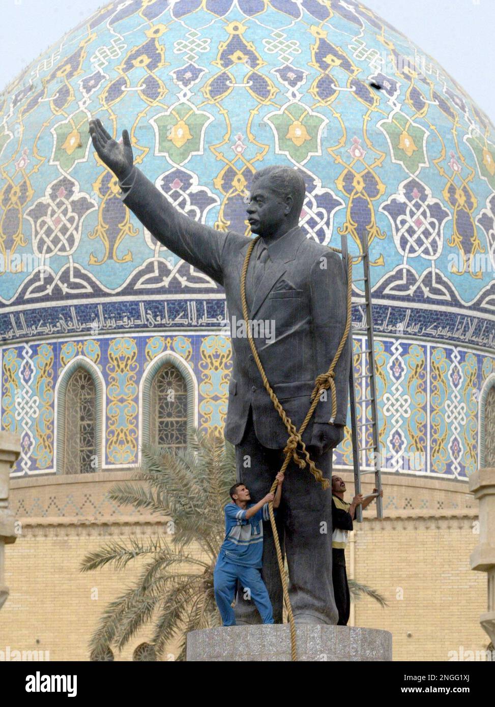 Iraqi civilians try to install a rope around the neck of a statue of ...