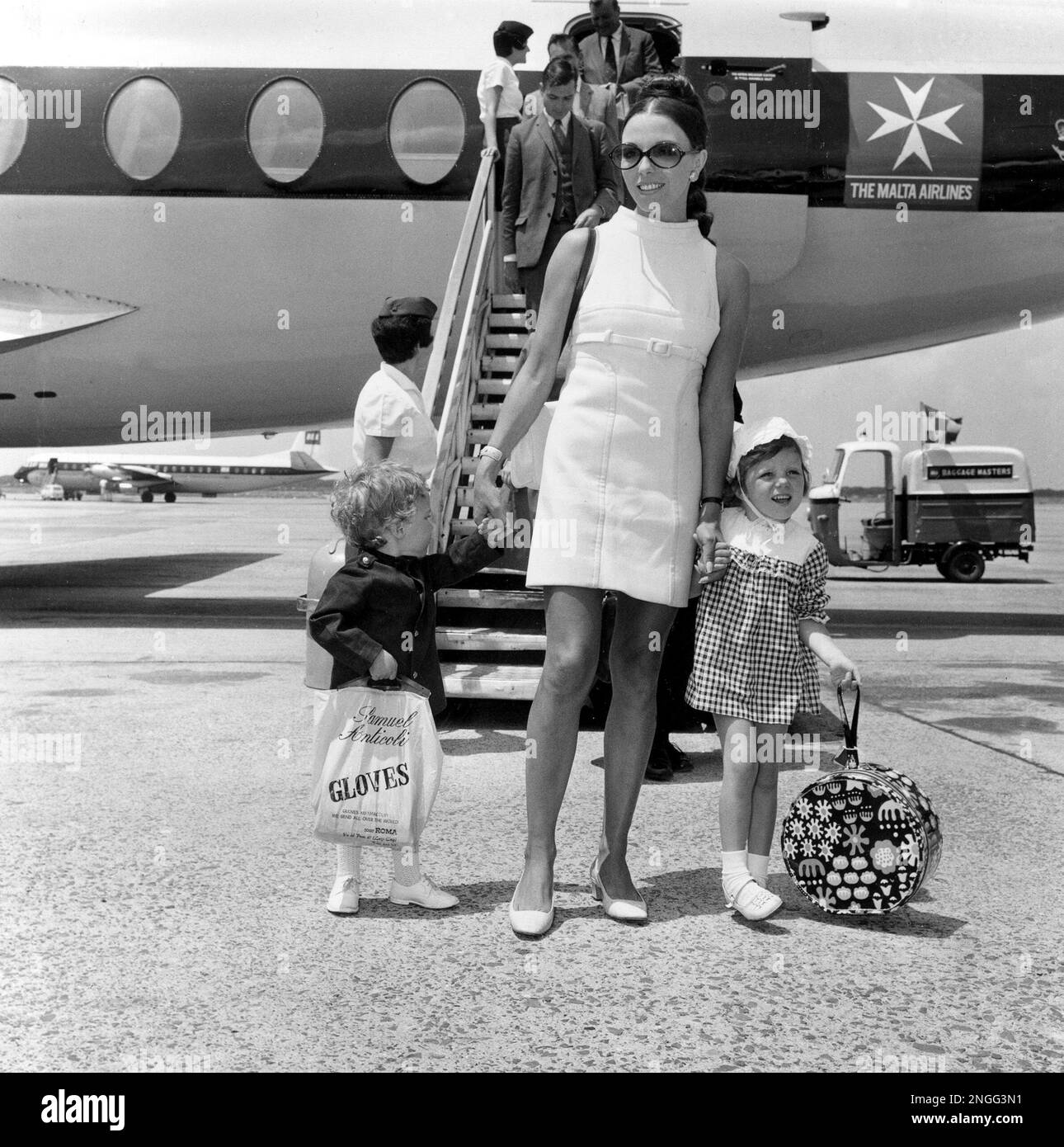 Actress Joan Collins holds the hands of her children Sacha, 3, left ...