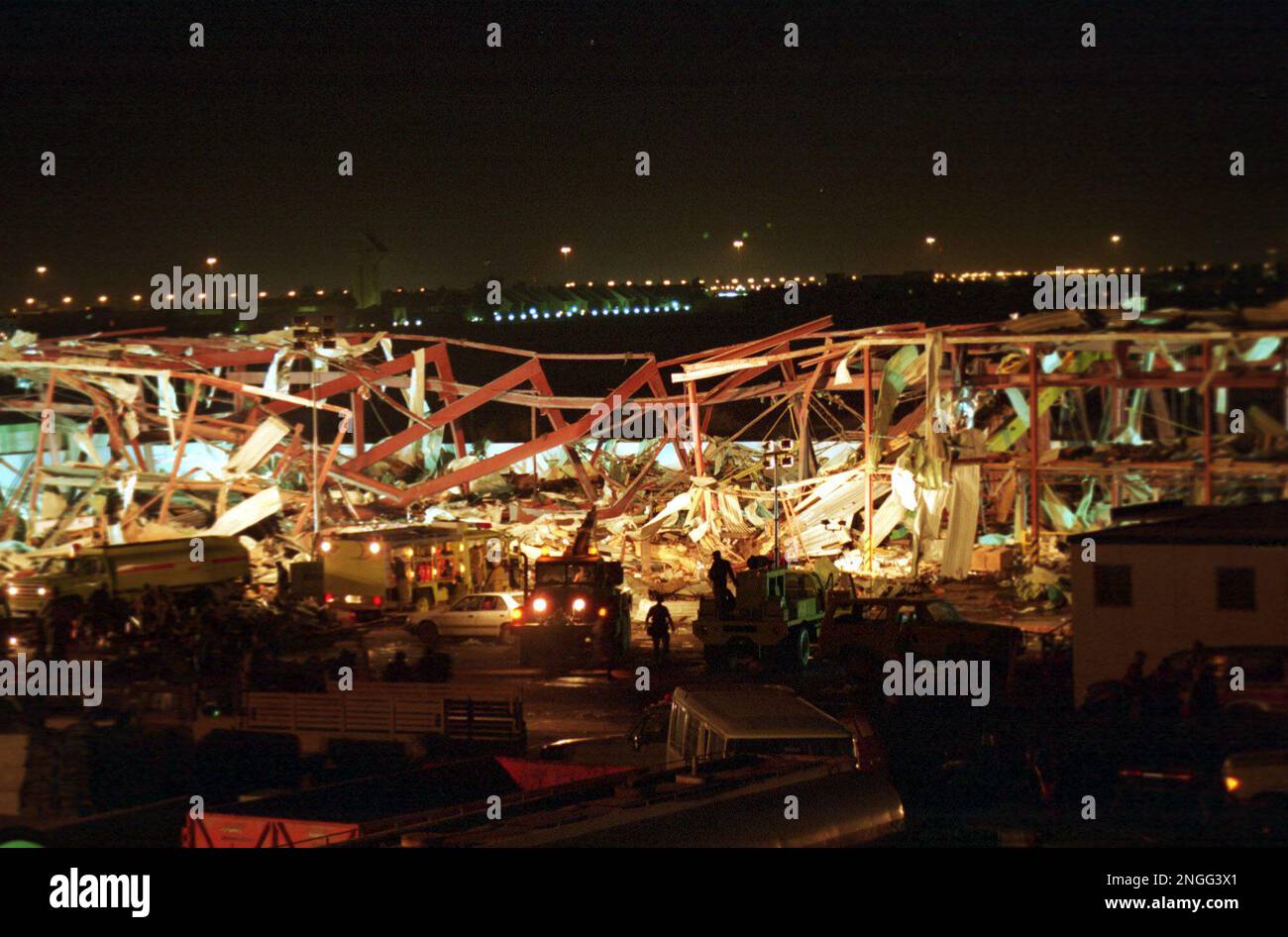 Workers using cranes and other equipment move through a heavily damaged ...