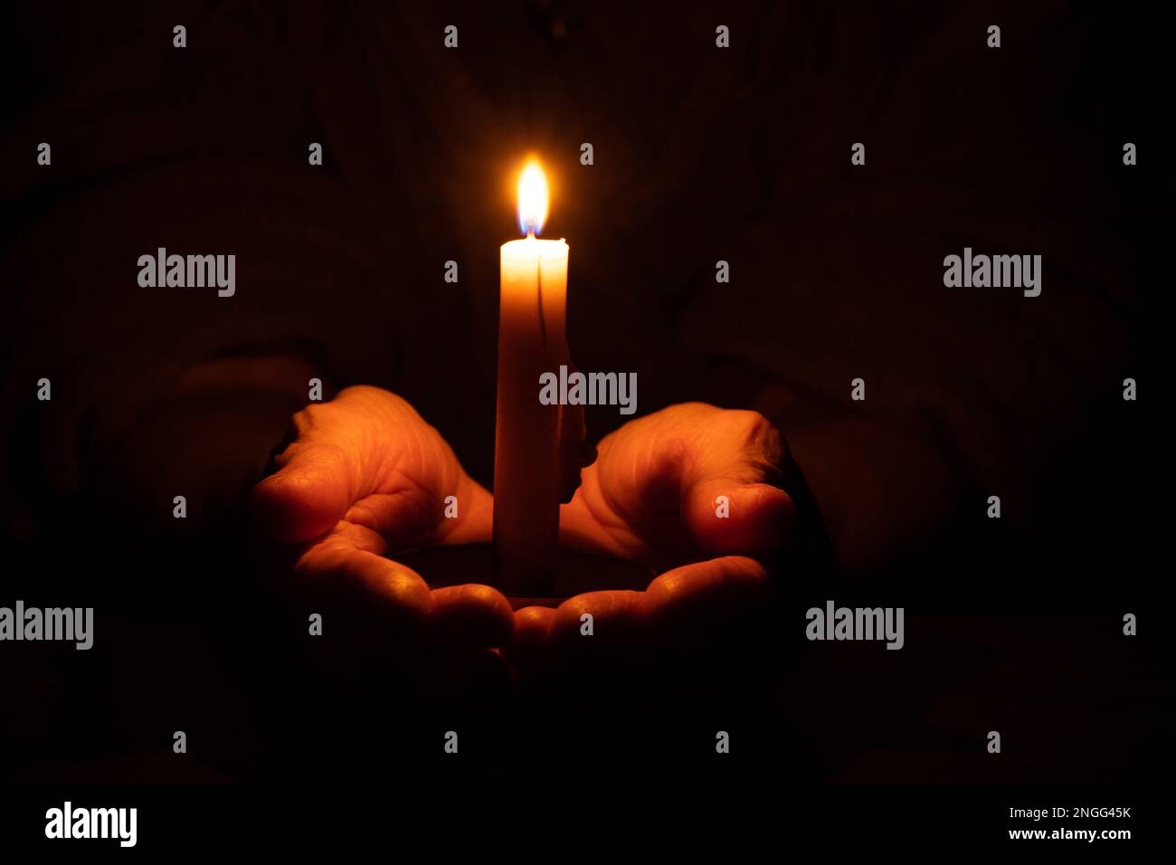 old woman's hands and candle flame in the dark, candle light, mourning ...
