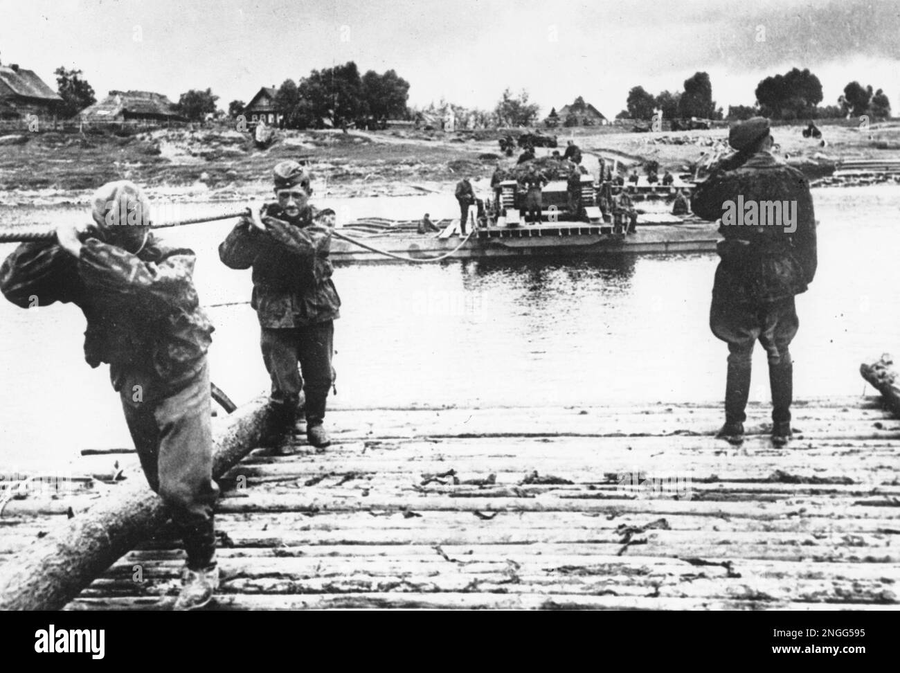 A Nazi SS officer watches as German soldiers pull on a tow-line to ...