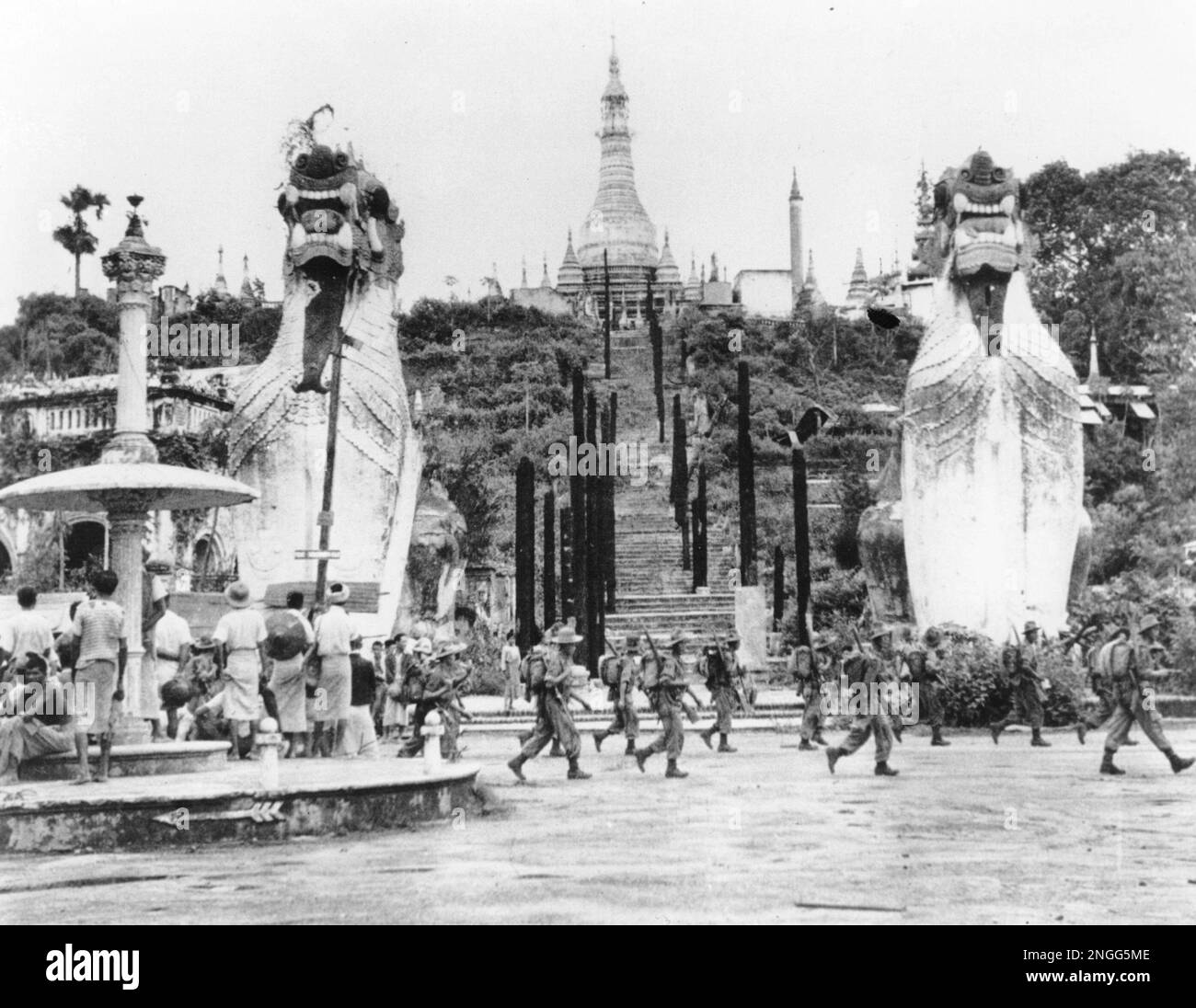 Gurkha soldiers of the British 14th Army move past two Chinthe statues ...